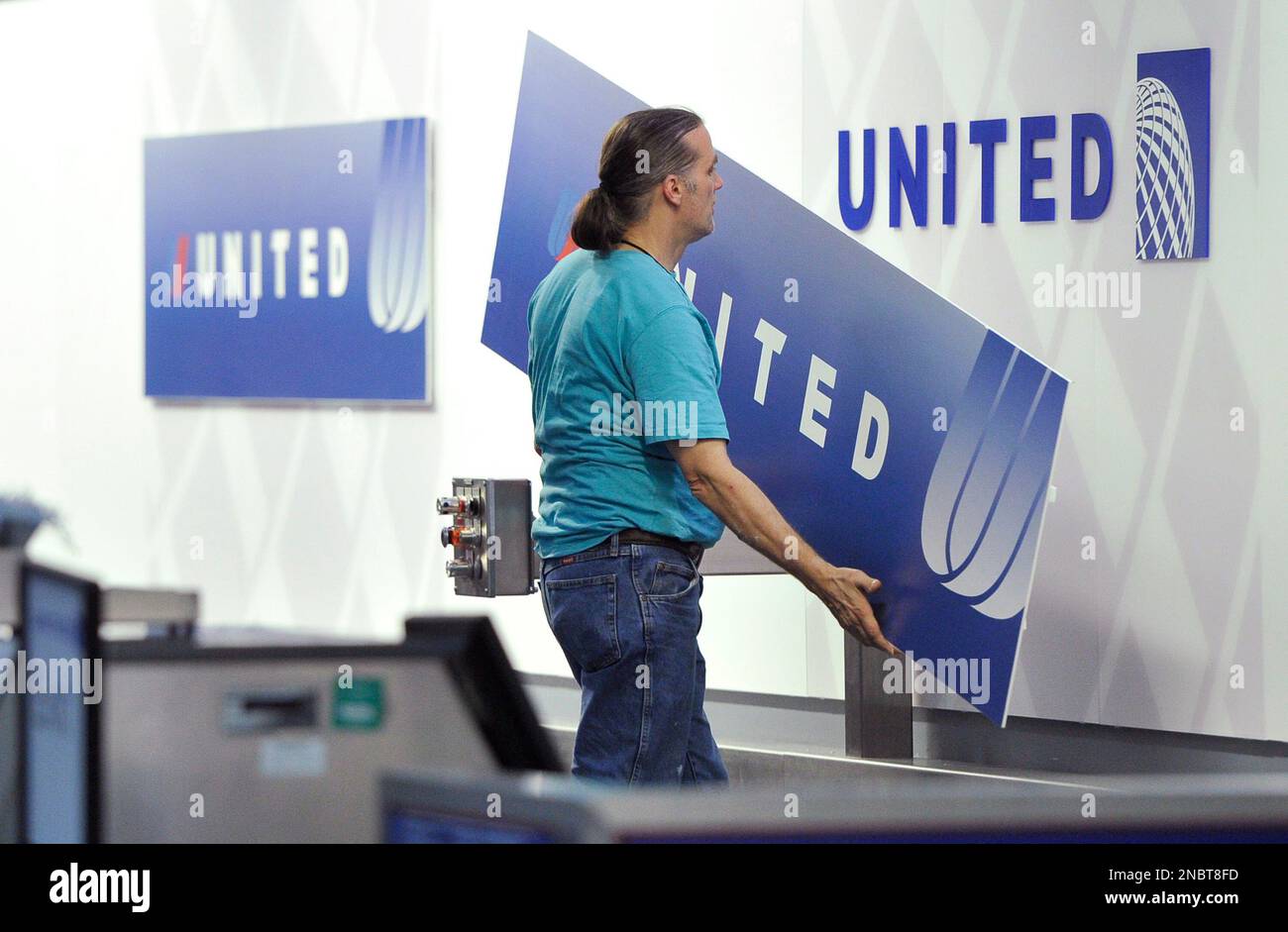 Steve Reininger removes a sign with the old United Airlines logo to ...