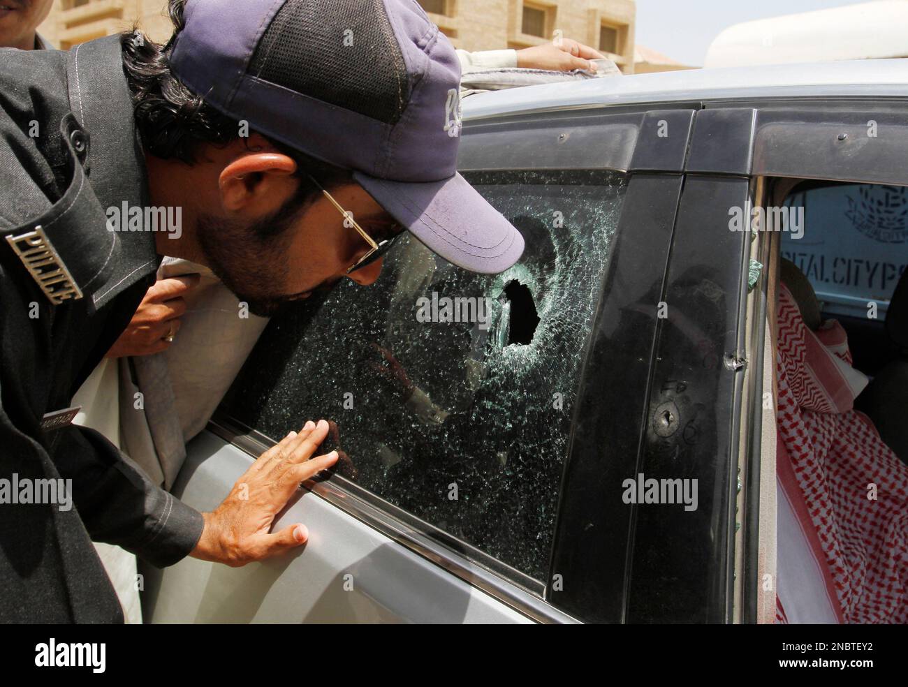 A Pakistani police officer examines a bullet hole on the car of a Saudi ...