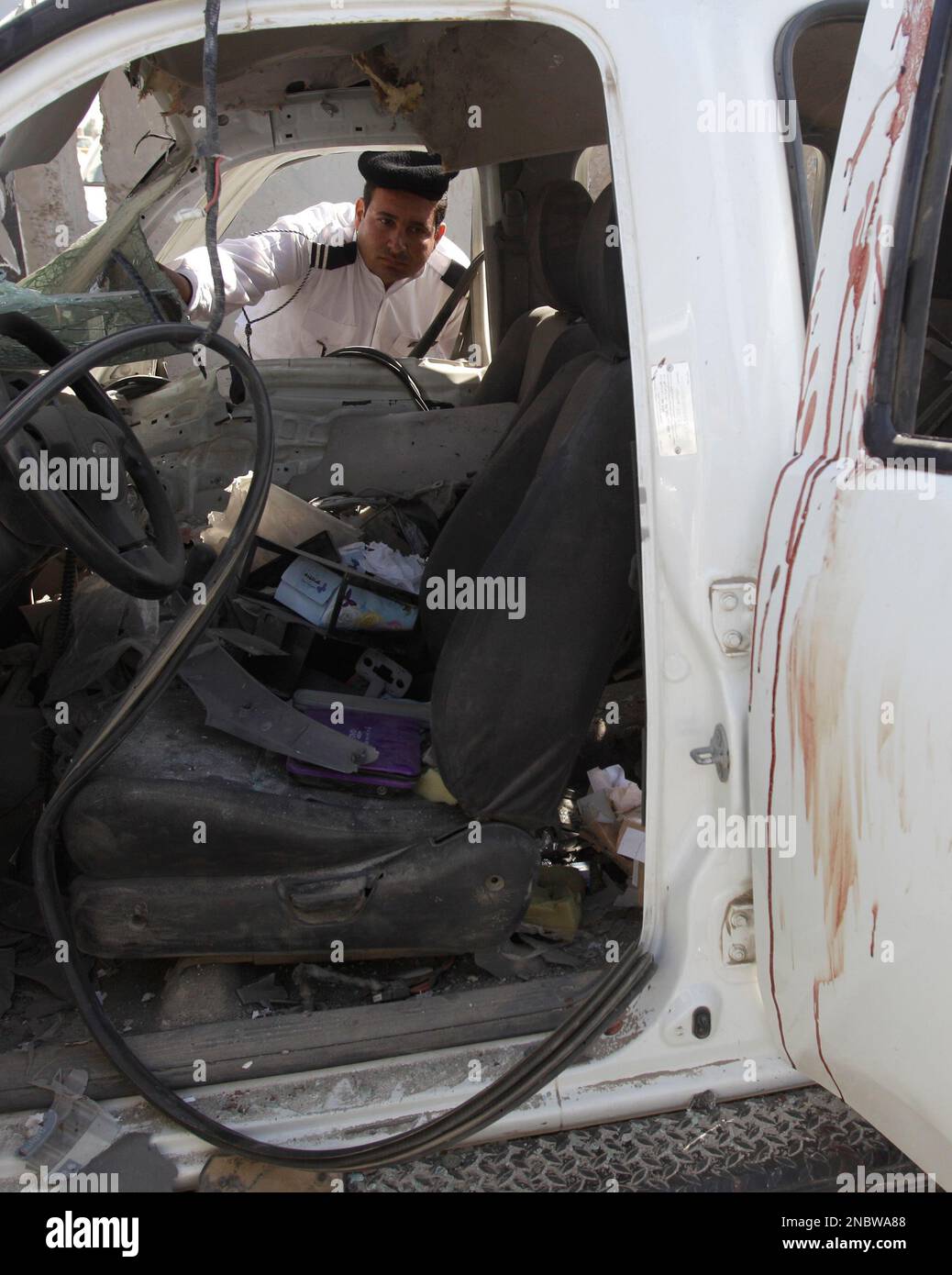 An Iraqi policeman inspects a damaged police car at the scene of a ...