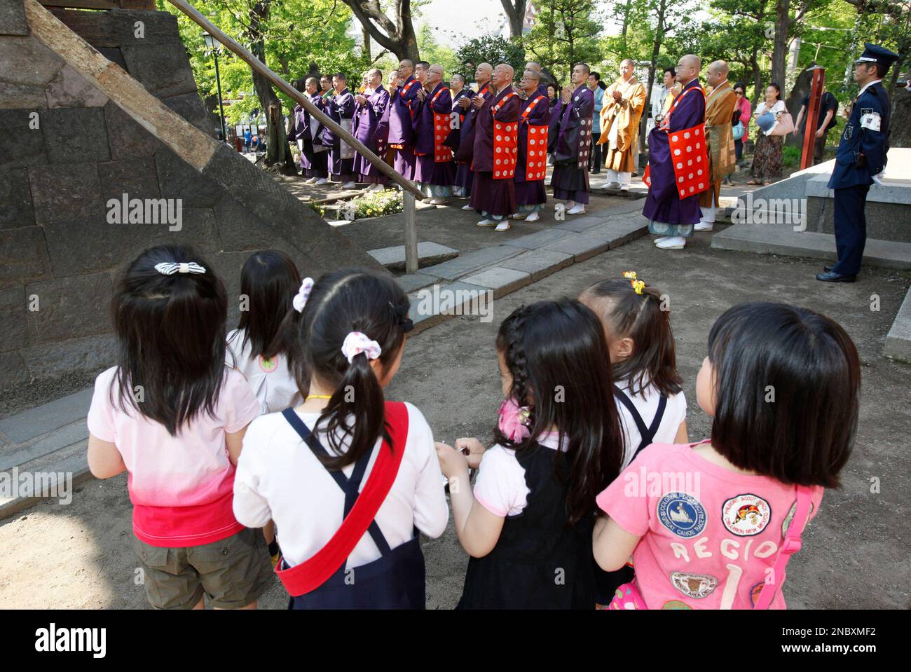 Children watch as Buddhist priests pray during a ceremony for the souls ...