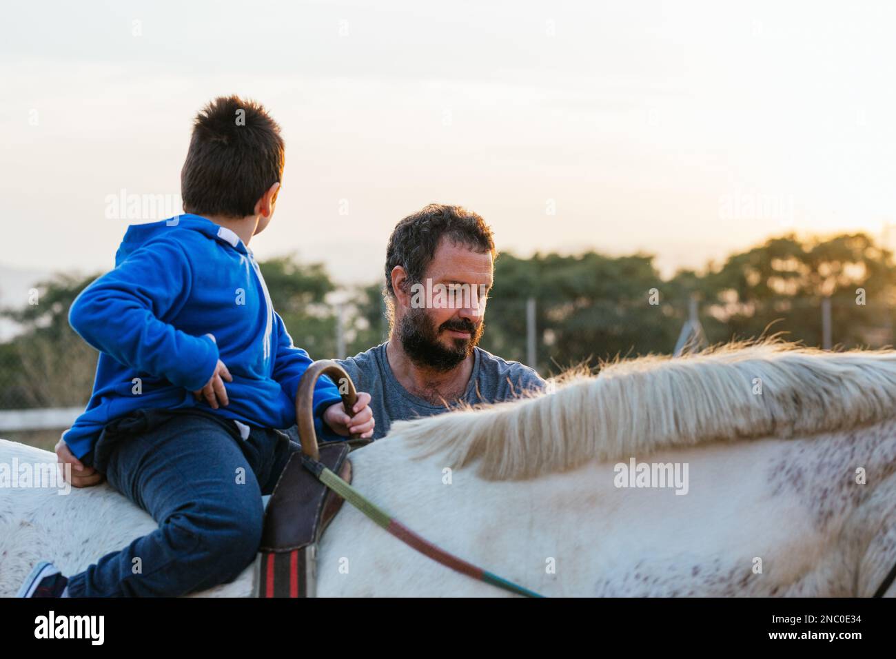 Ein Junge mit Behinderungen genießt es, draußen auf einem Pferd in ...