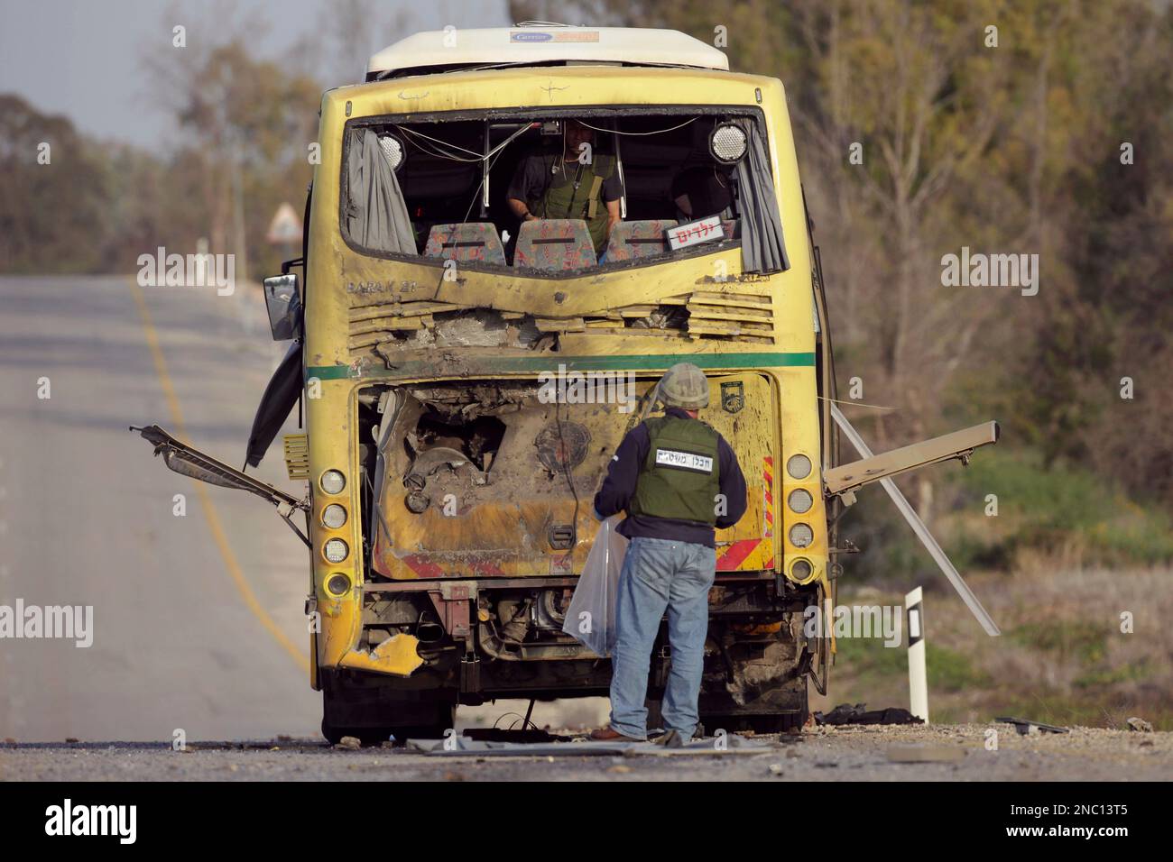 Israeli sappers inspect a school bus hit by an anti-tank missile fired ...