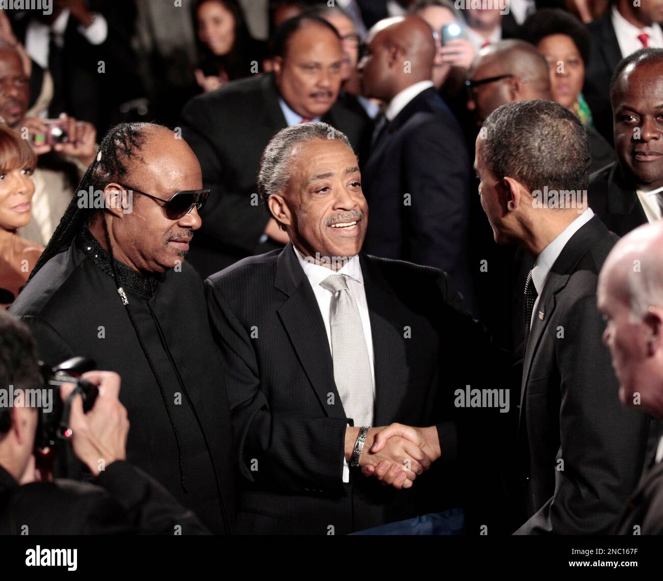 President Barack Obama, right, greets recording artist Stevie Wonder, left, and Rev. Al Sharpton ...