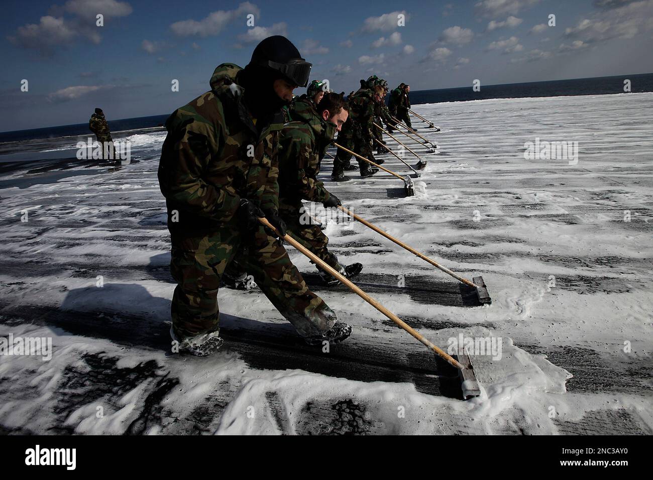 U.S. Navy crew members mop up the flight deck to remove radioactive ...