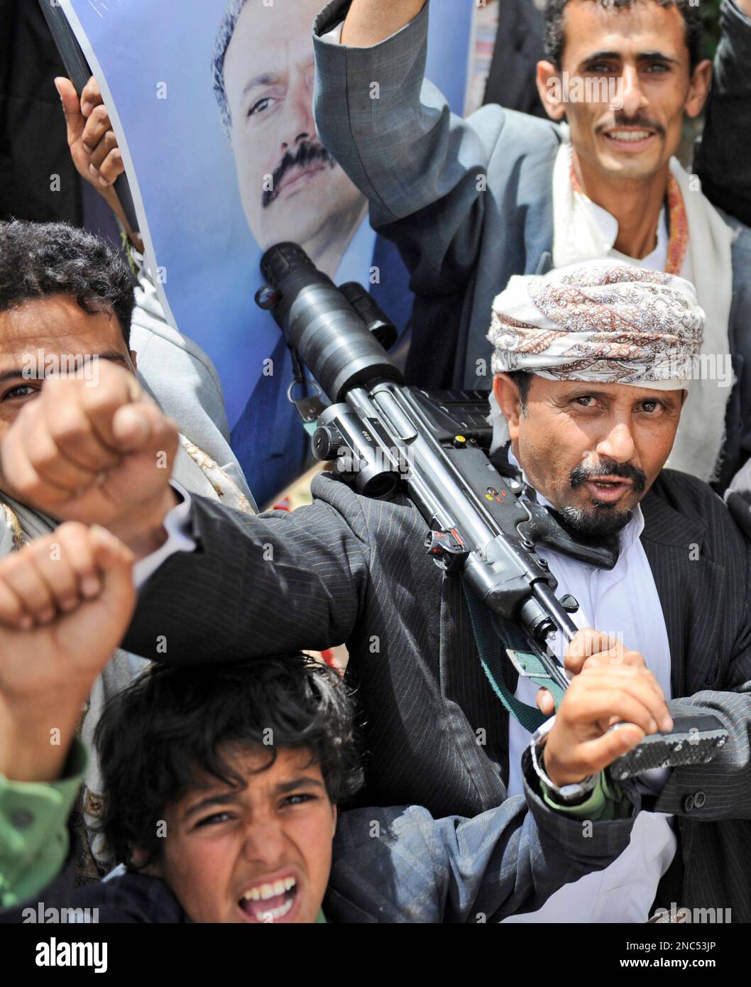 Supporters of Yemeni President Ali Abdullah Saleh one carrying a weapon ...