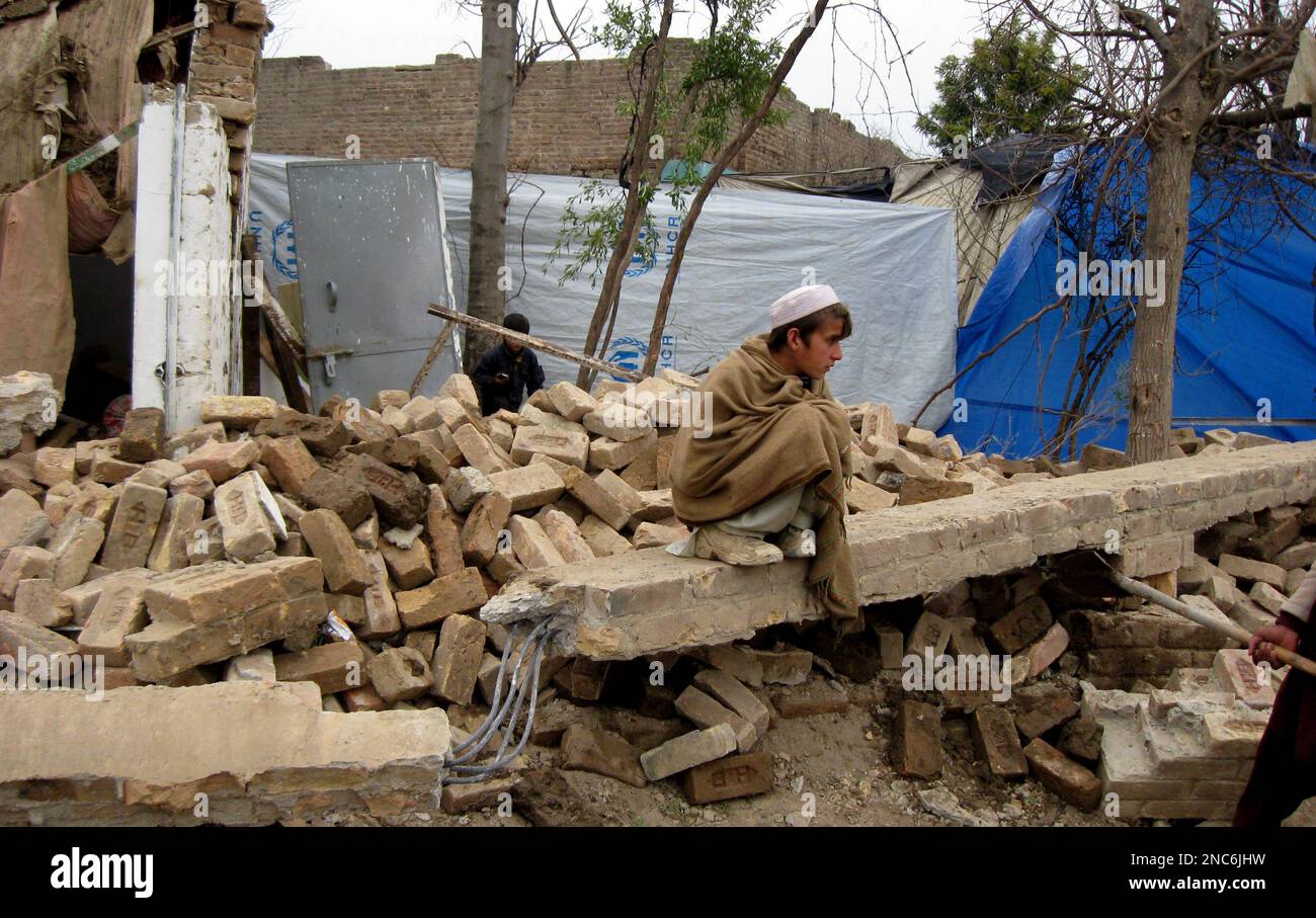 A Pakistani boy sits on the remains of his house destroyed by a bomb ...
