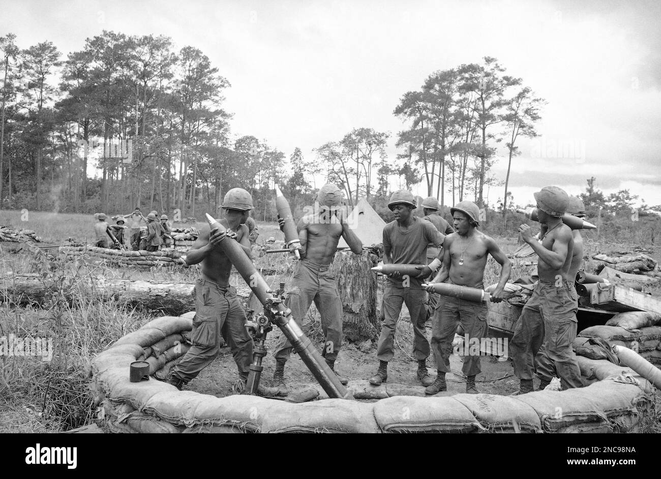 Crew of 81mm mortar coordinate commands as shell is dropped down tube ...