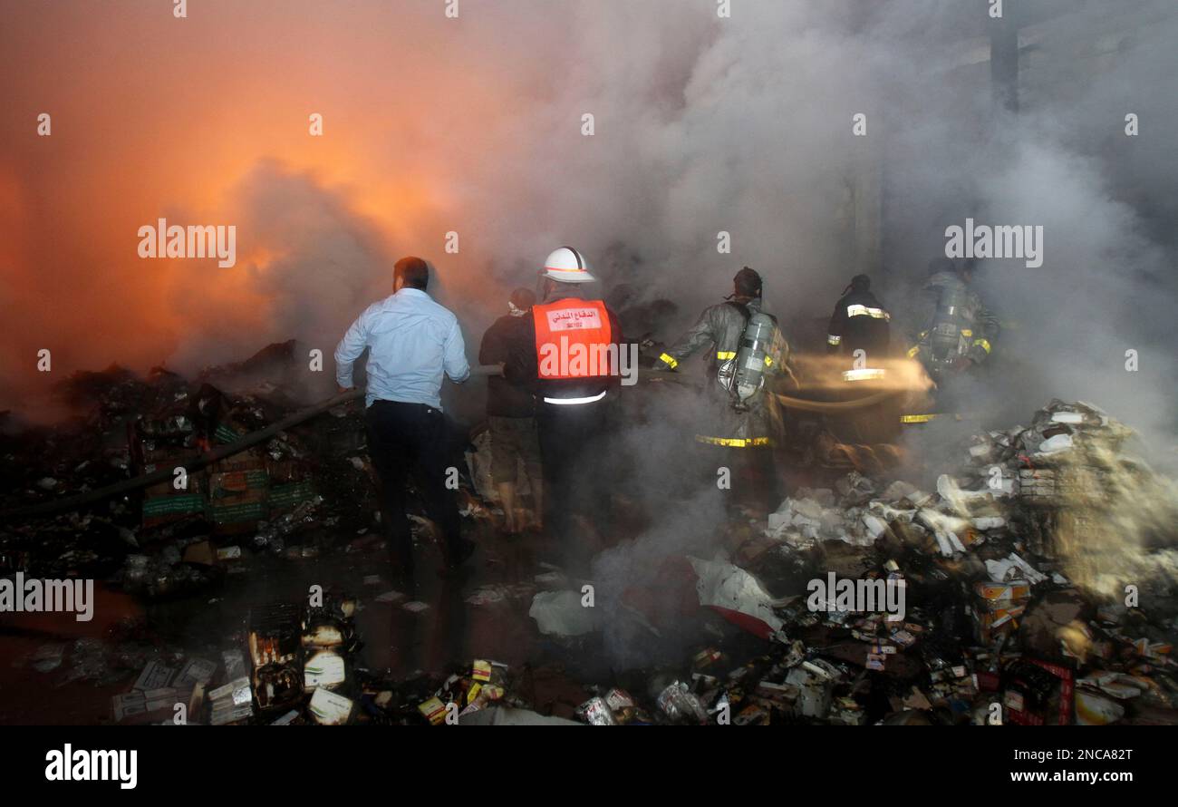 Palestinian firefighters try to extinguish a fire at a burning medicine ...