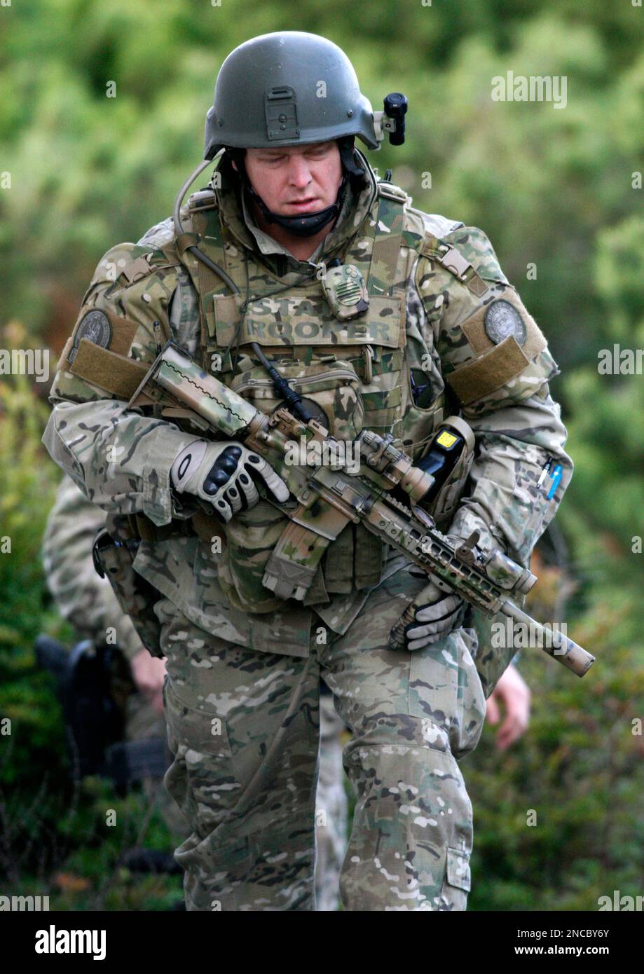 A member of the Oregon State Police SWAT team searches near a home in ...