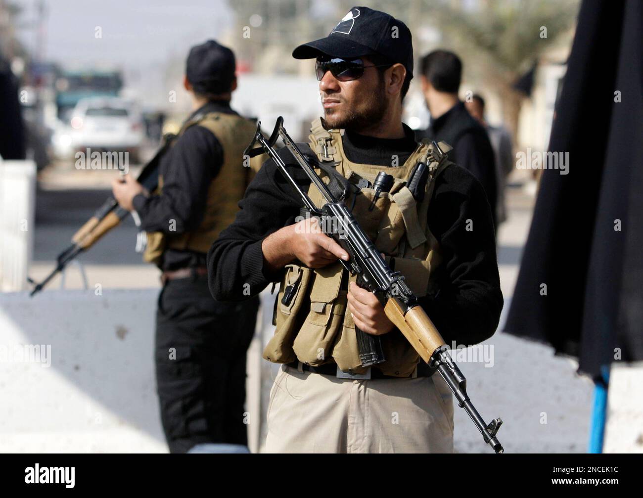 Security guards stand outside the home of radical Shiite cleric Muqtada ...
