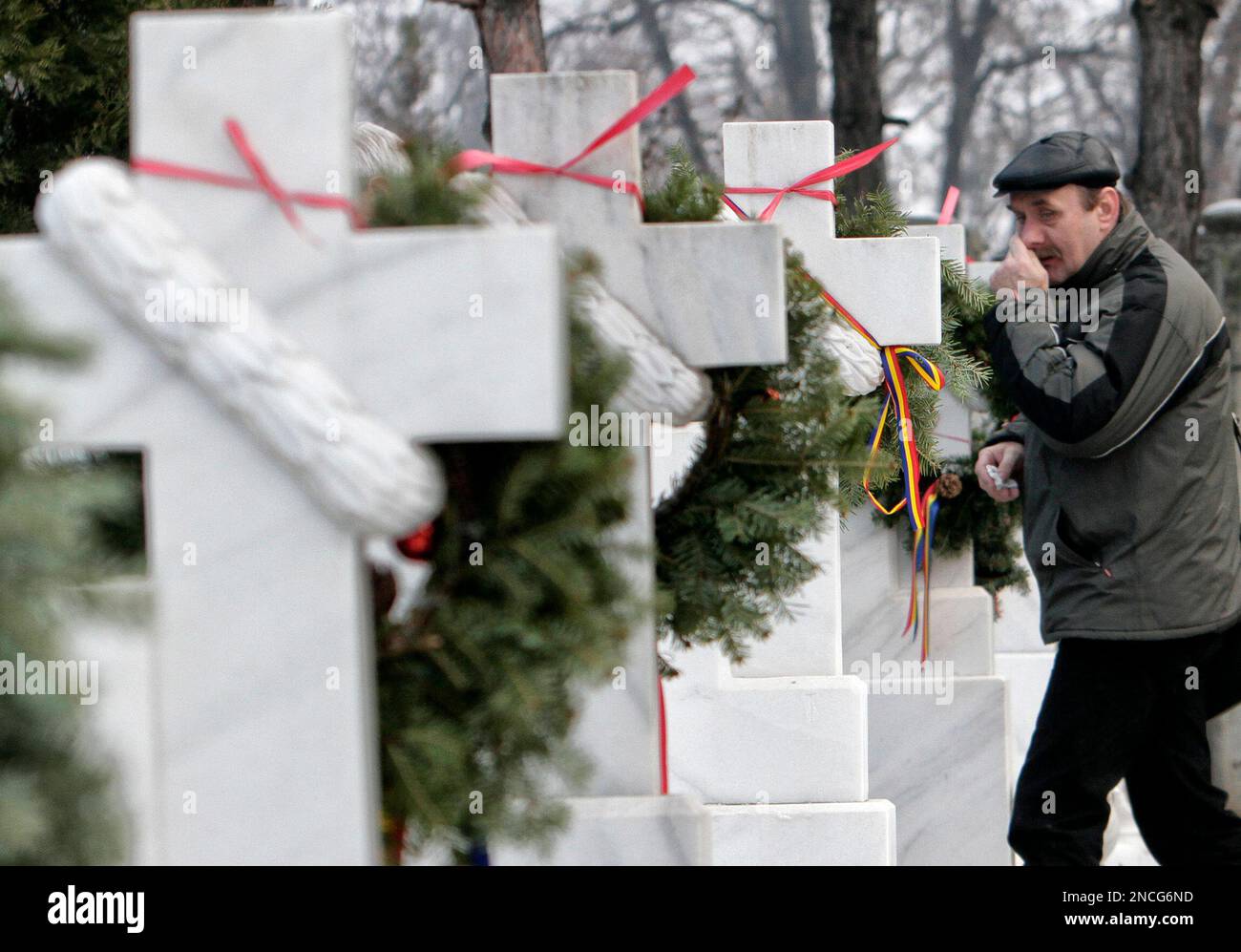 A man passes by graves during a commemoration attended by few people ...