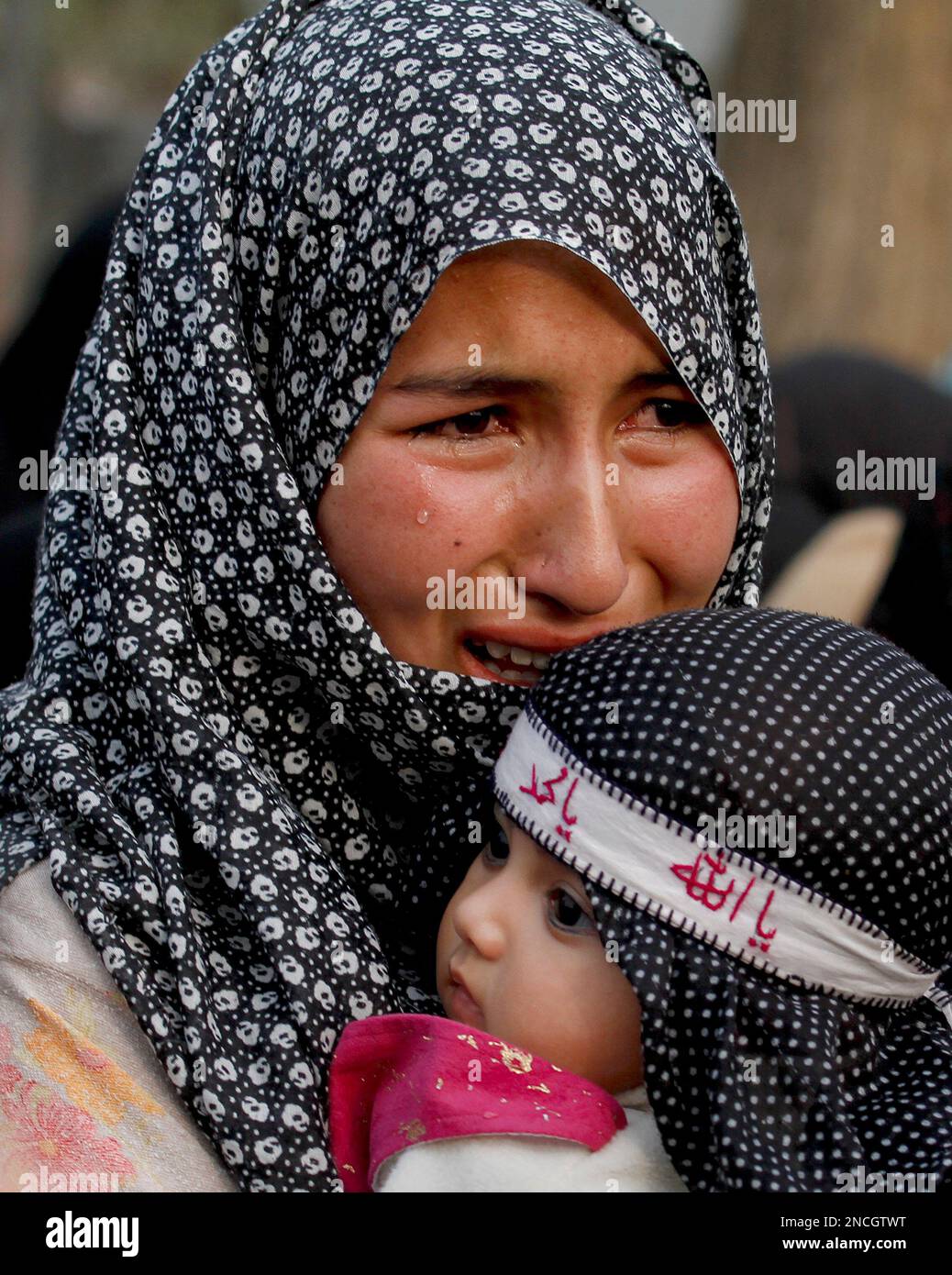 A Pakistani Shiite Muslim woman holds her child as she mourns the death ...