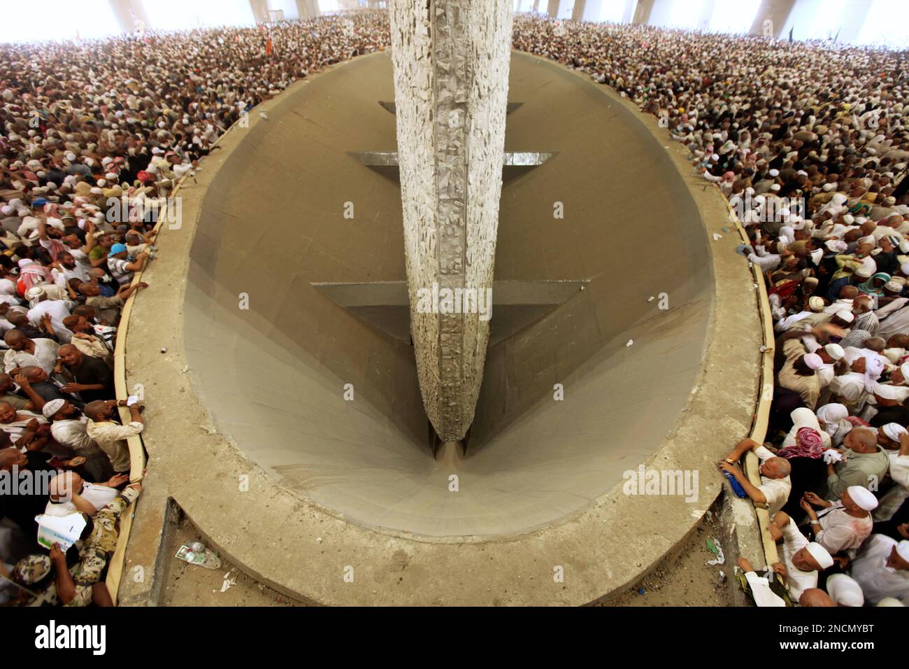 Muslim pilgrims cast stones at a pillar, symbolizing the stoning of ...