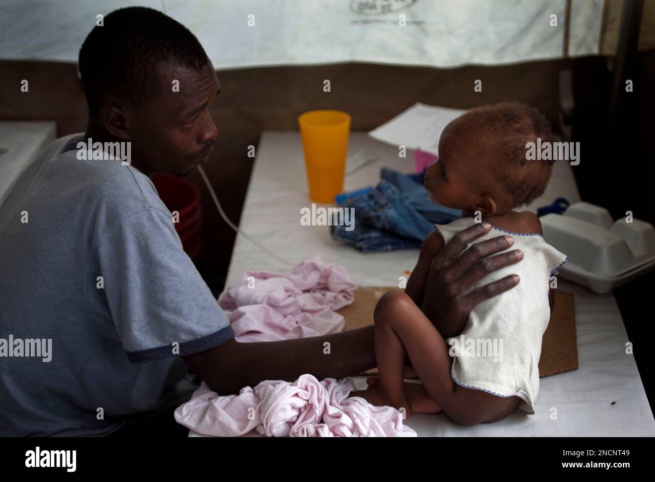 A child with cholera symptoms rests as his father looks on at the ...