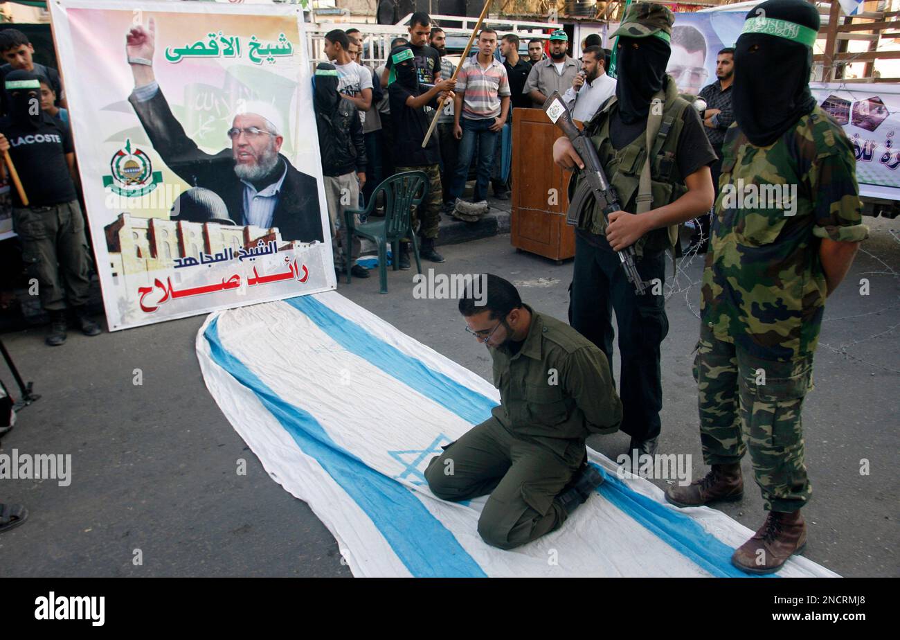 Masked Palestinian Hamas militants stand behind a Palestinian ...