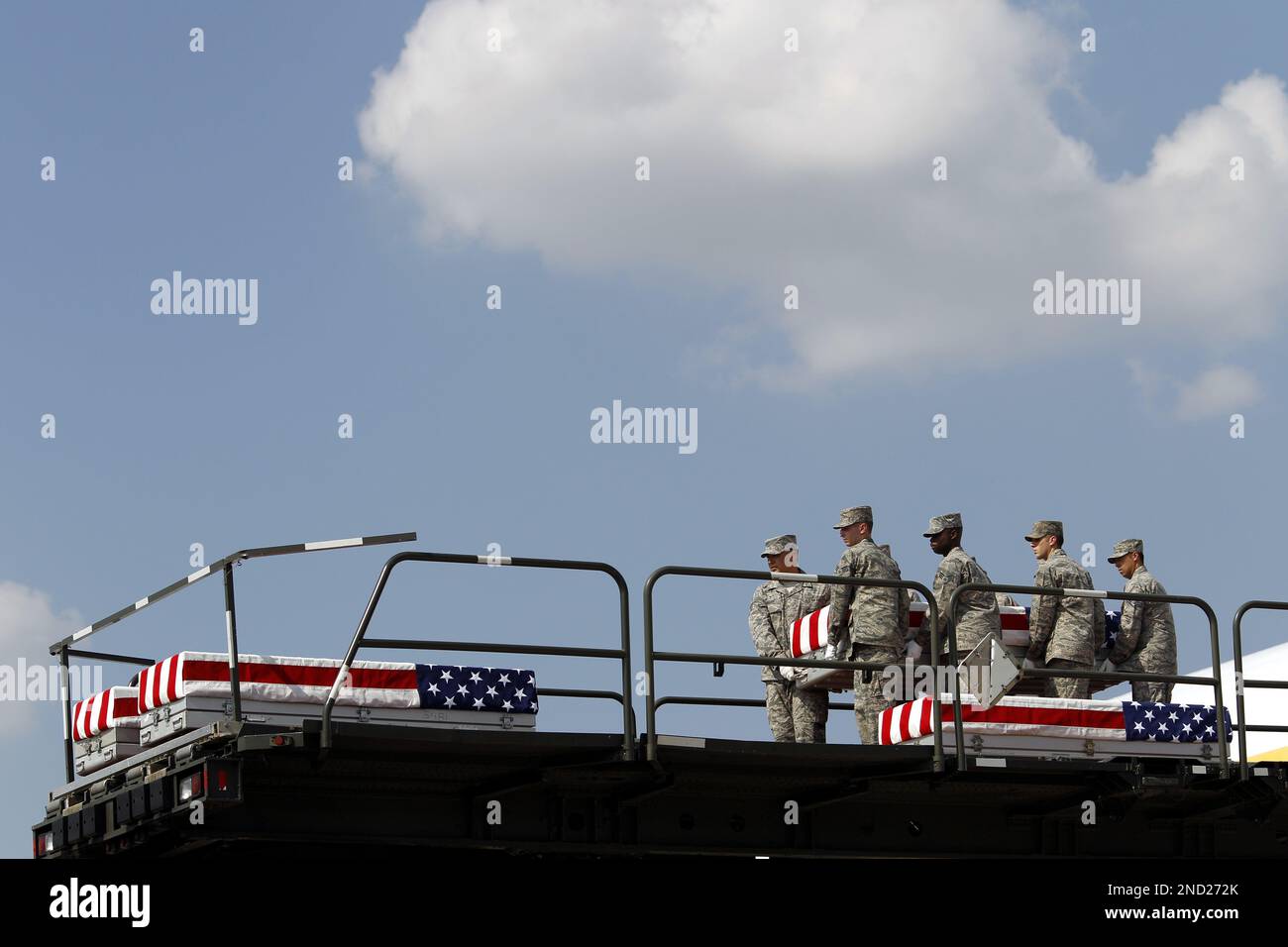 An Air Force carry team carries the transfer case containing the ...