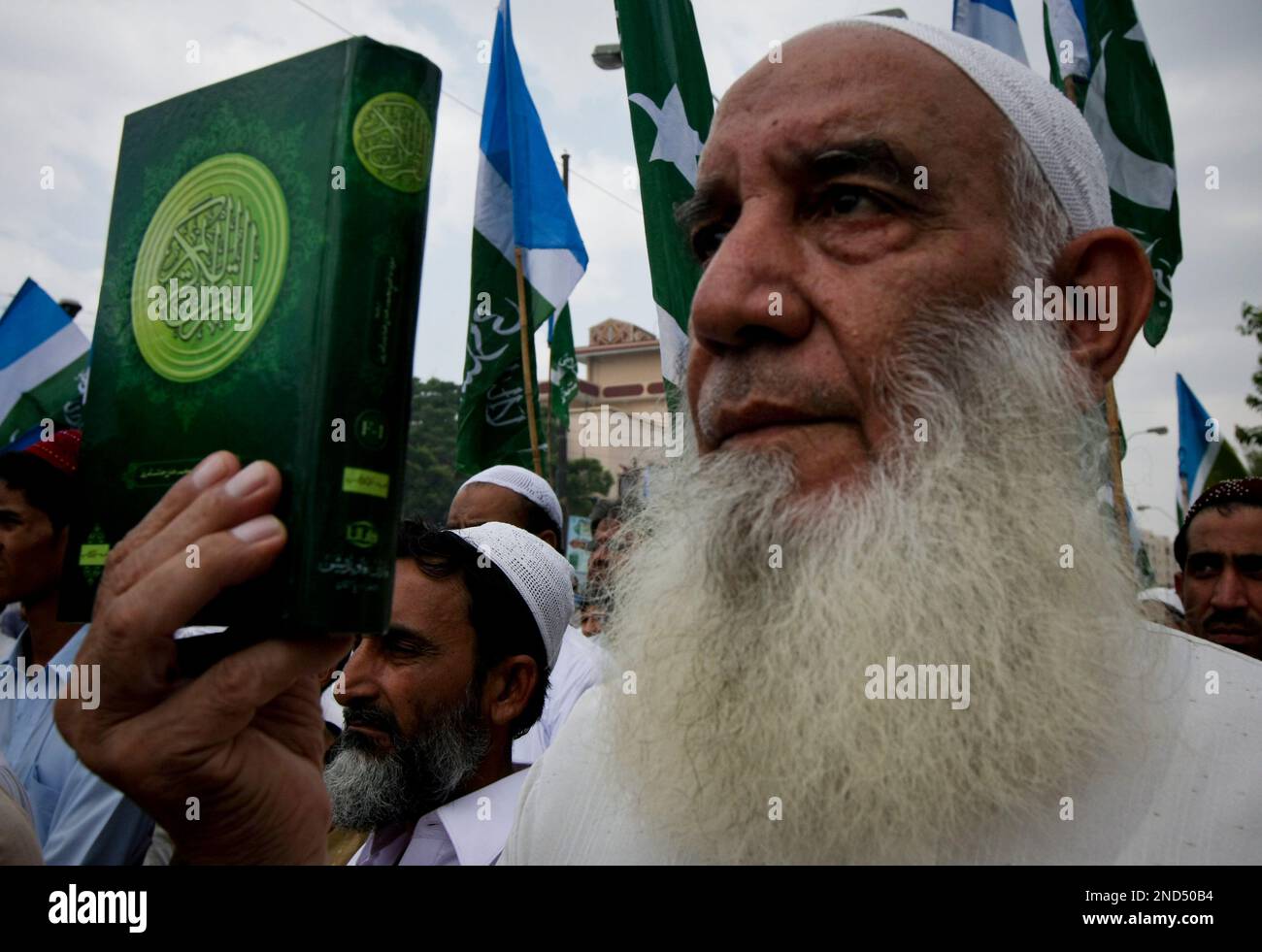 A supporter of Pakistani religious party Jamat-e-Islami holds a copy of ...