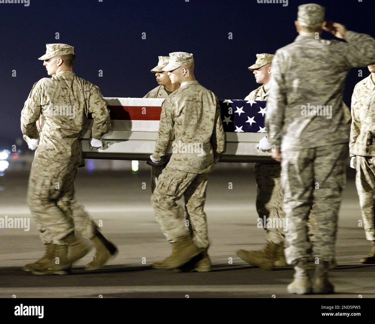 A Marine carry team carries the transfer case containing the remains of ...
