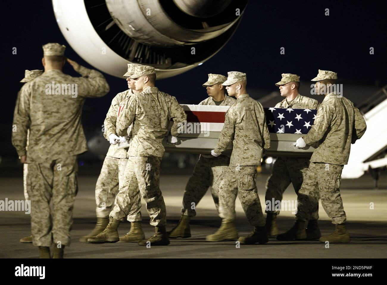 A Marine carry team carries the transfer case containing the remains of ...