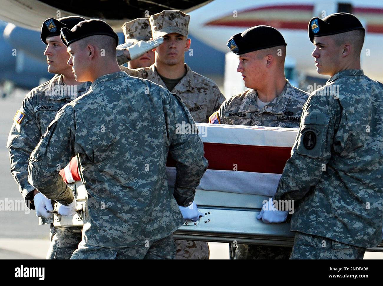 A member of a Marine carry team salutes, center, as an Army carry team ...