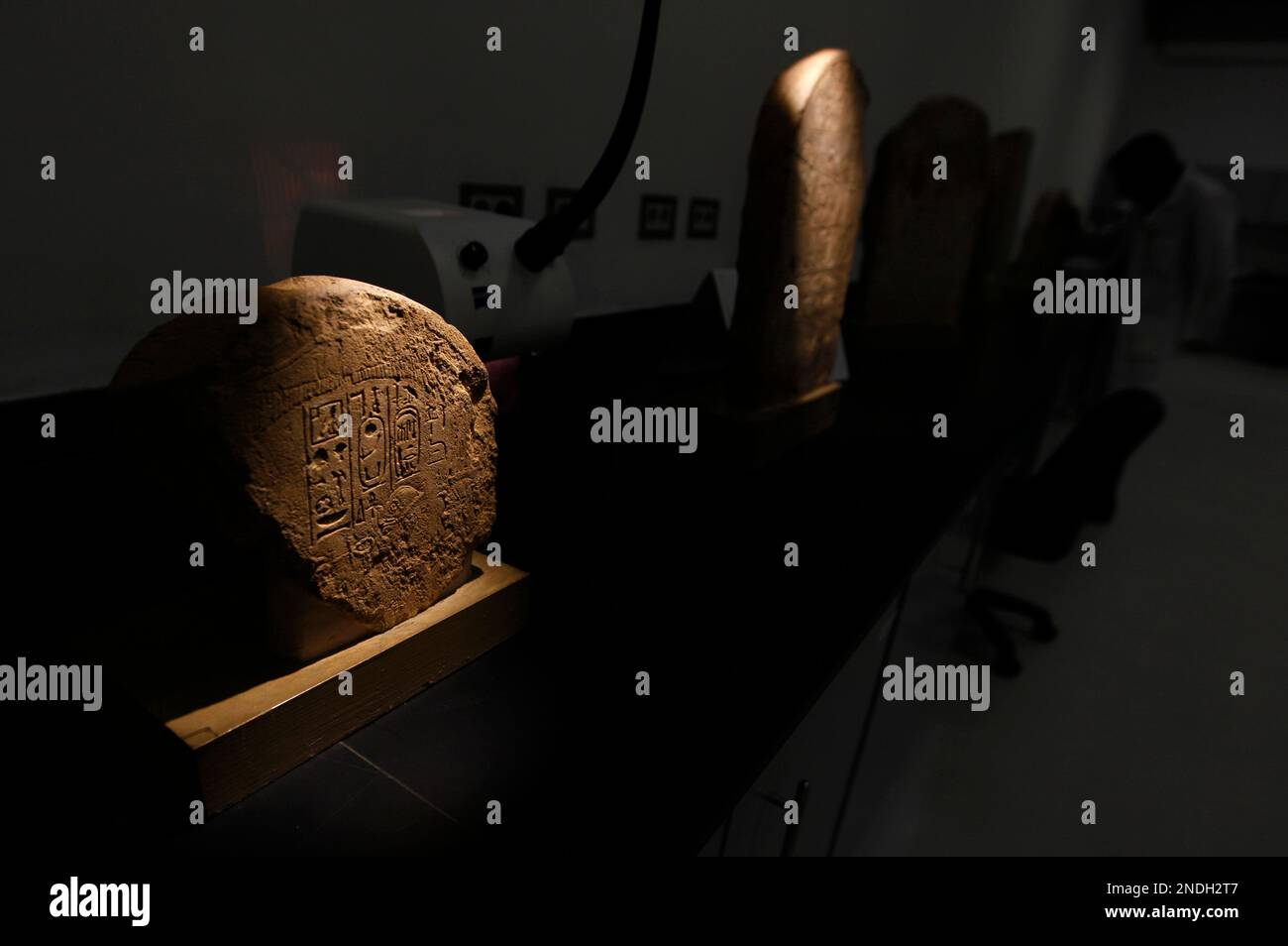 An Egyptian archeological technician works by a restored pharonic stela ...