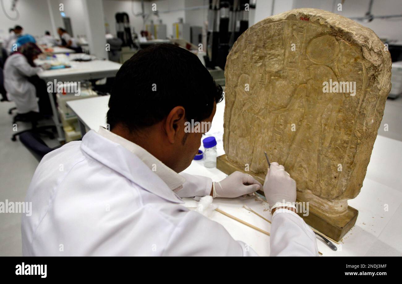 An Egyptian archeological technician works on a pharaonic late period ...