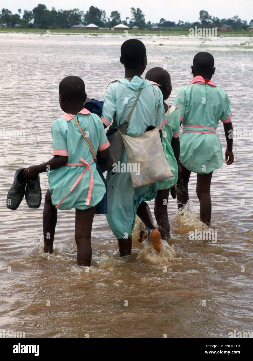 School girls walk through the flood water, after the river Sondu Miriu ...