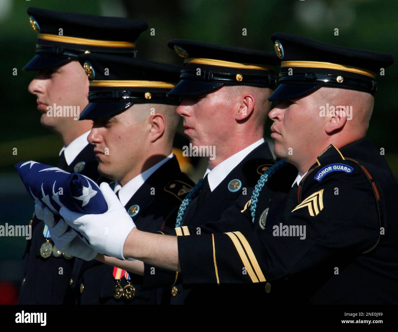 An Army honor guard passes the folded flag that draped the coffin of ...