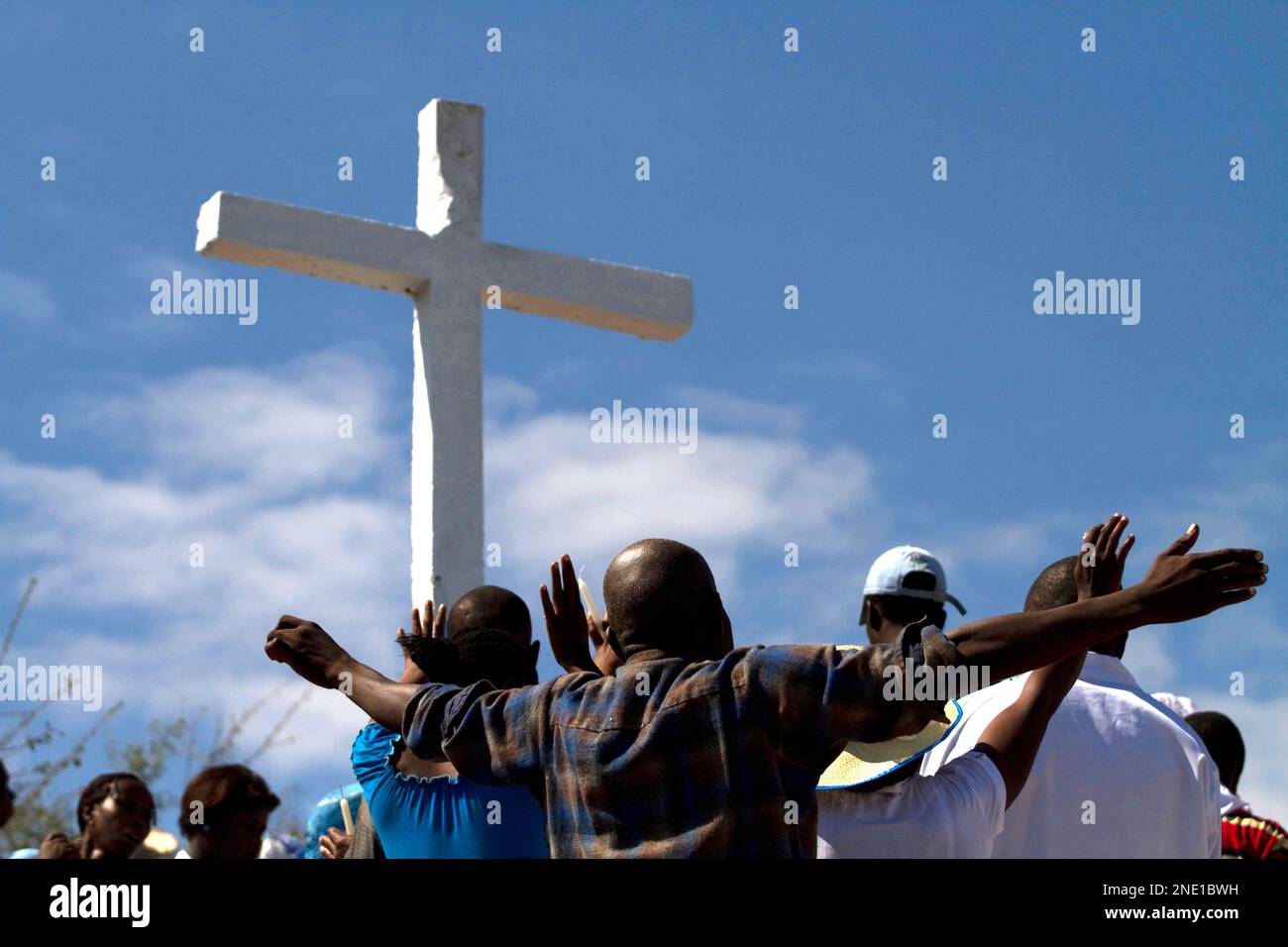 People gestures in front of a cross during a Holy Week procession in ...