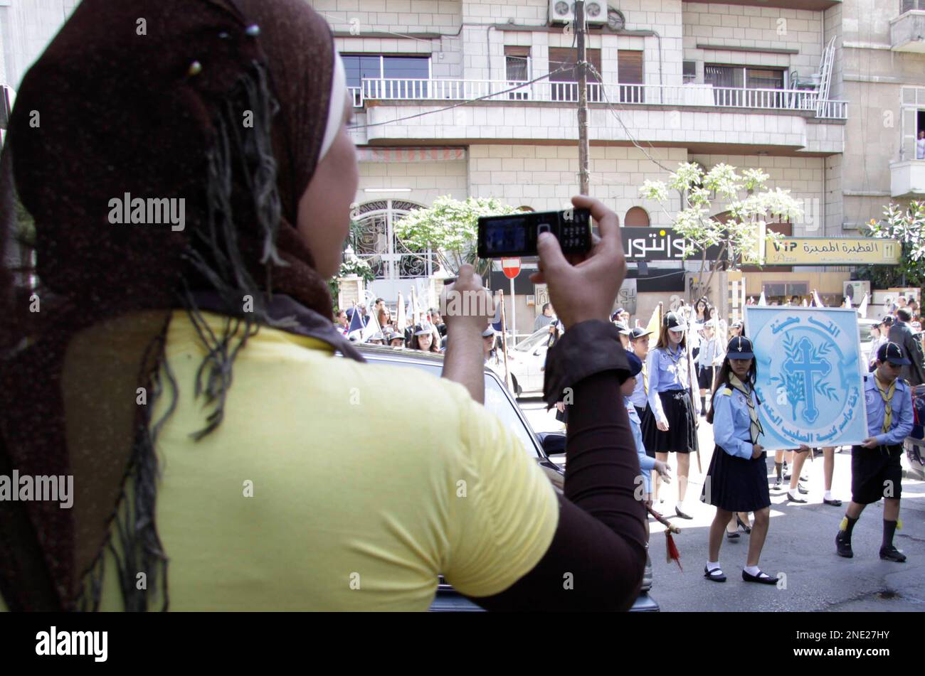 A Syrian takes a picture of the Syrian Christian scouts as they hold a ...