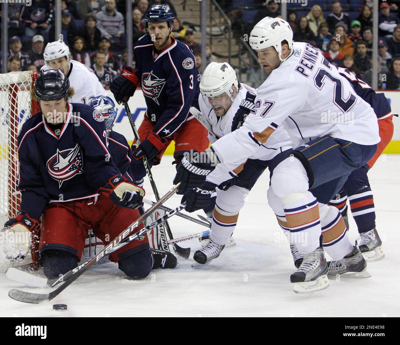 Columbus Blue Jackets' Mike Commodore, left, knocks the puck away from ...