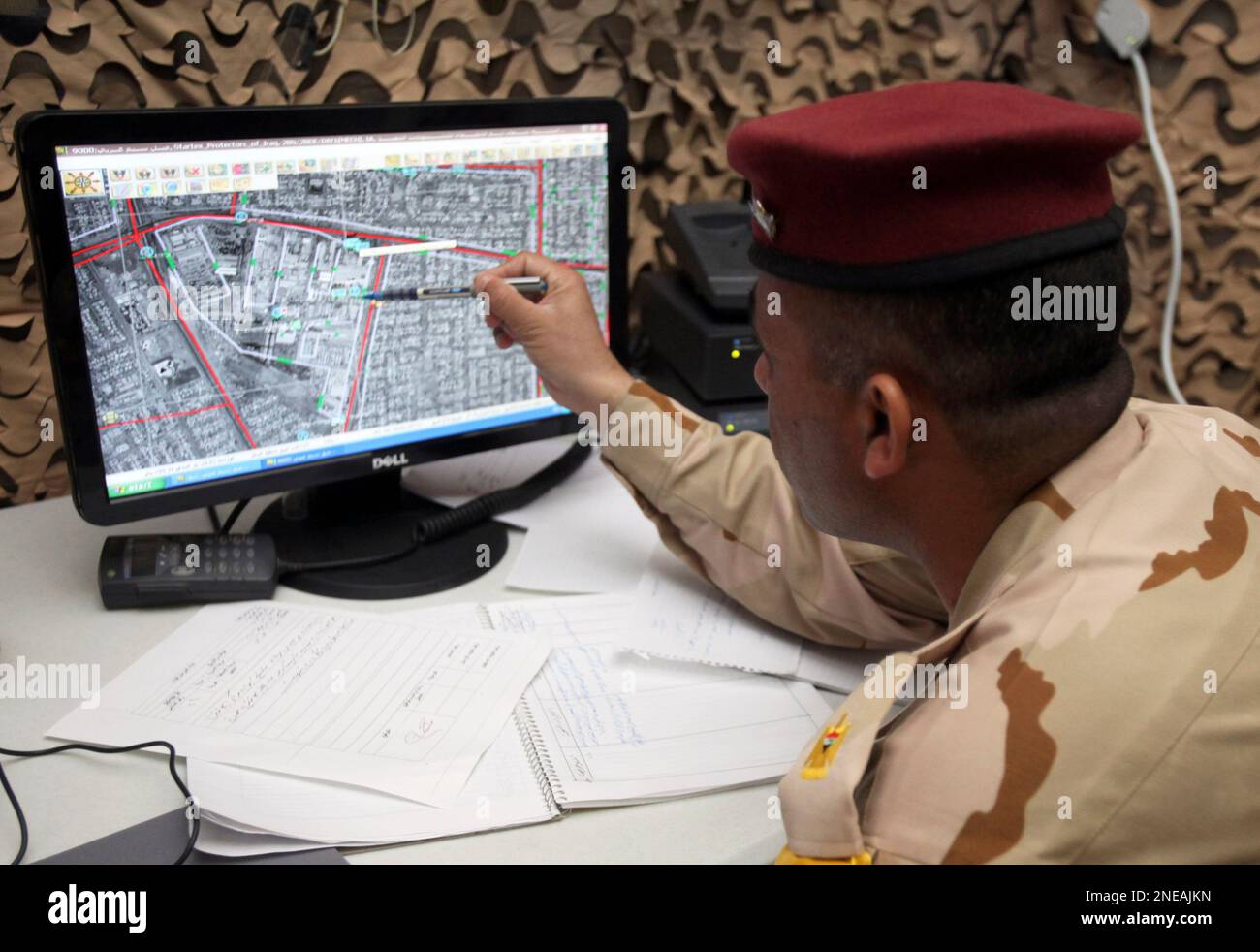 An Iraqi Army officer hunches over a computer screen, looking at a map ...