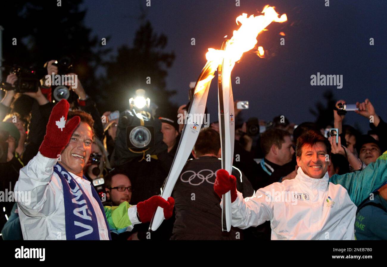 California Gov.Arnold Schwarzenegger, left, passes the Olympic flame to ...