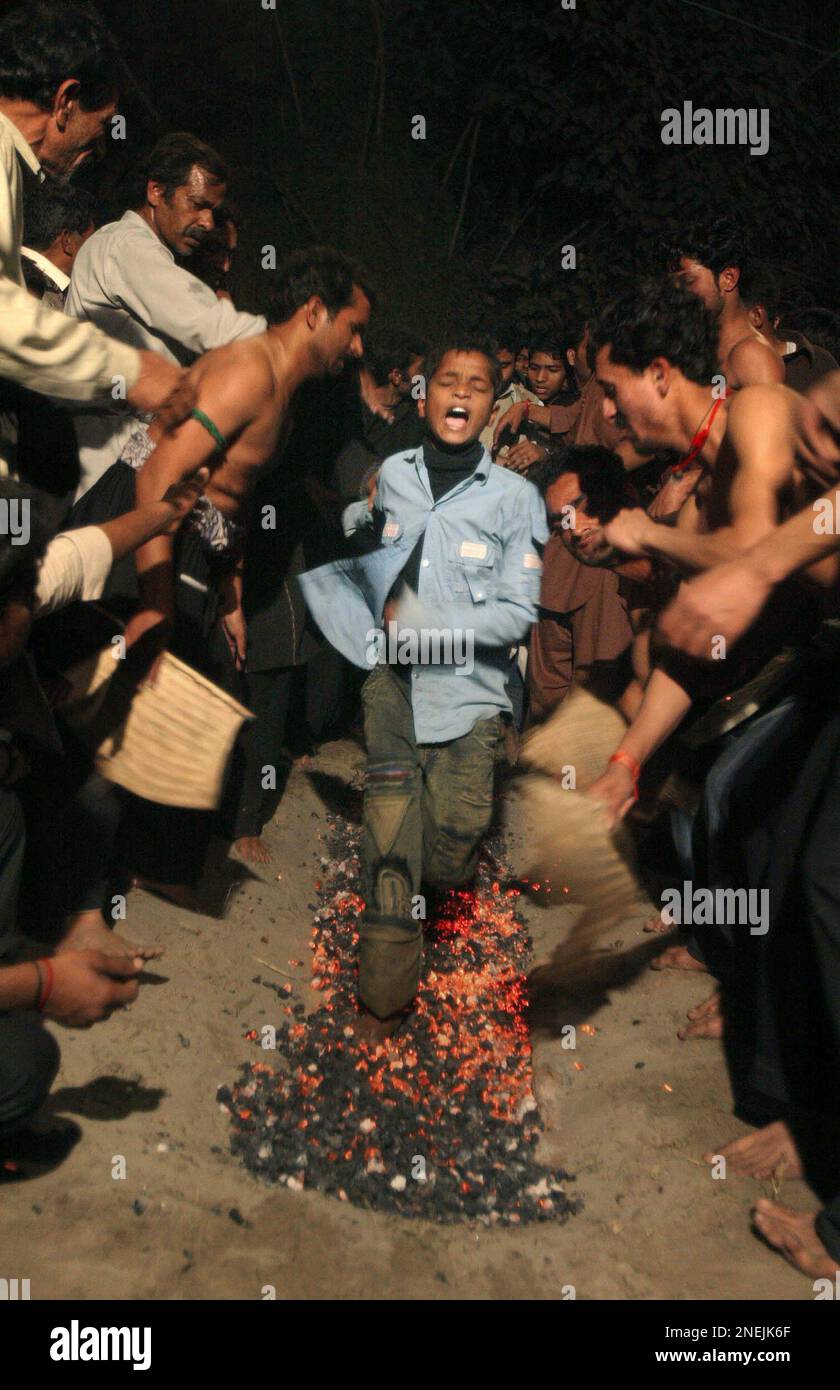 A Pakistani Shiite Muslim boy walks on burning coal as his religious ...