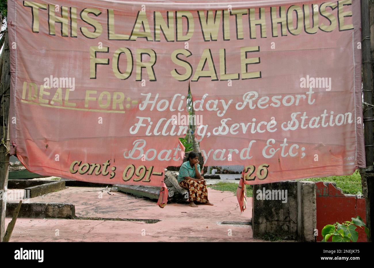 A Sri Lankan tsunami survivor sits on the debris of her house on the ...