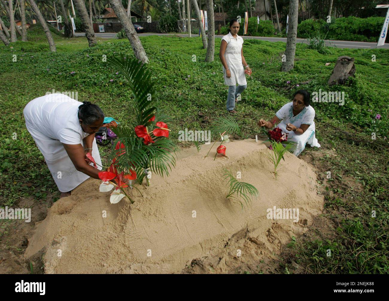 Sri Lankan tsunami survivors pay tribute to a mass grave on the fifth ...