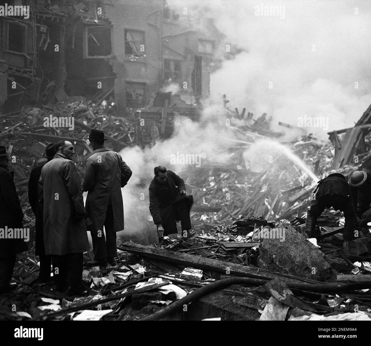 Firemen playing hoses on to the smouldering wreckage of a building ...