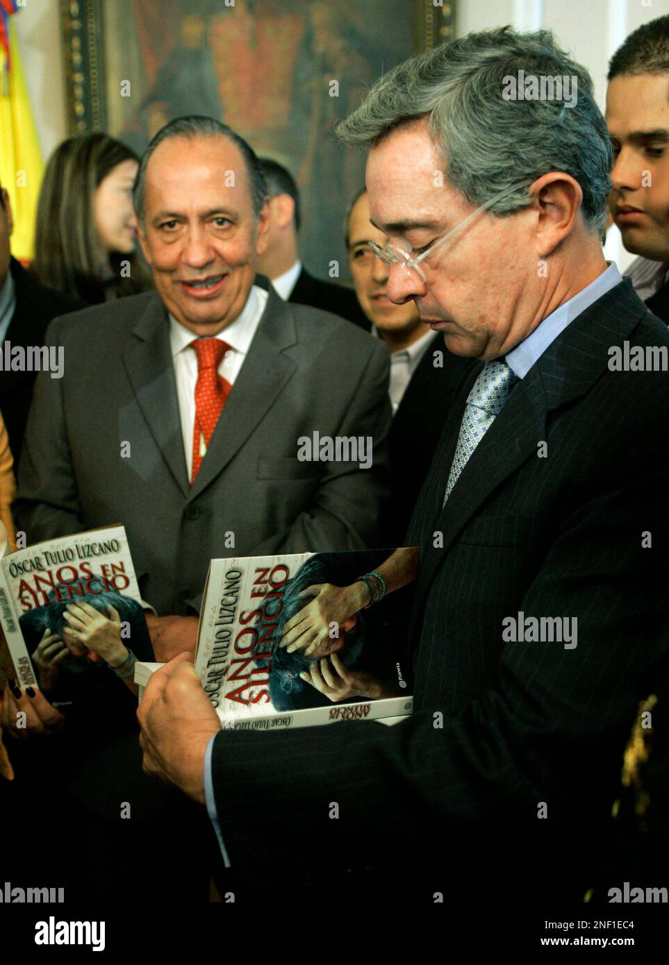 Colombia's President Alvaro Uribe, front, signs a copy of a book ...