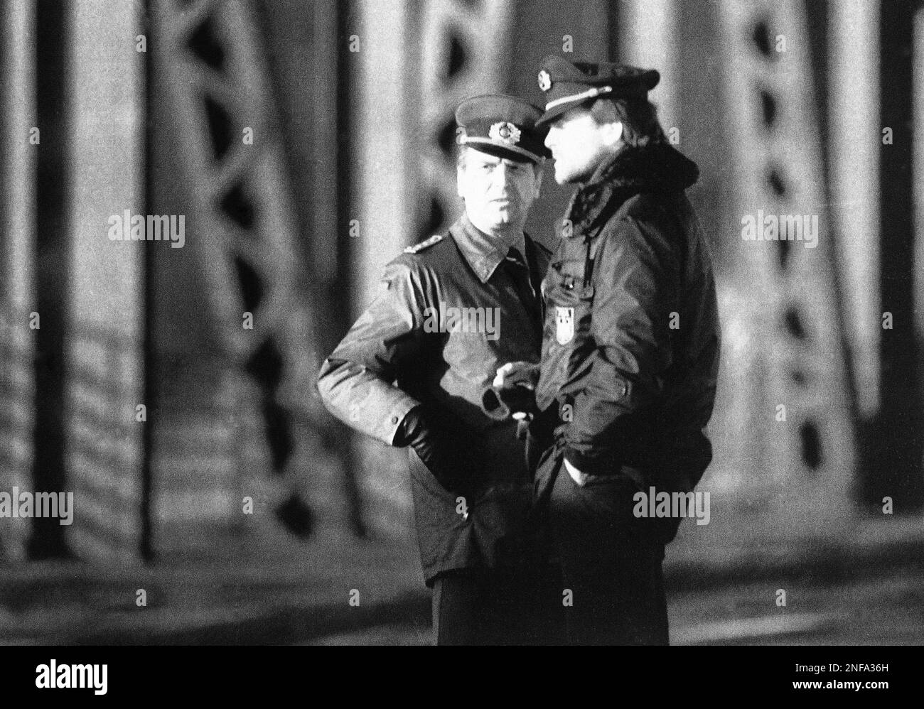 An East German border guard, left, talks with a West German police ...