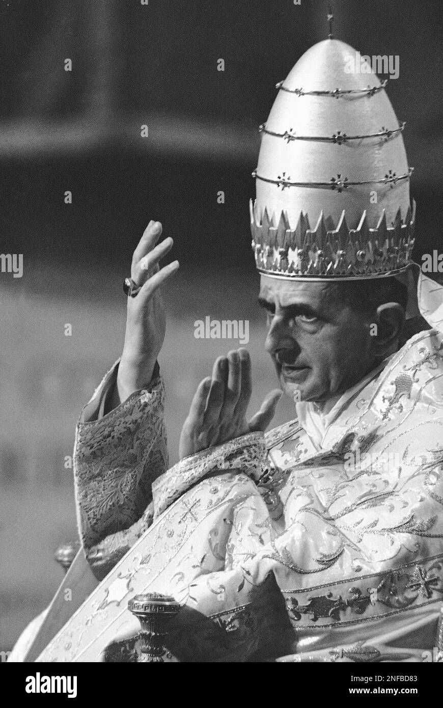 Pope Paul VI, wearing full pontifical robes and the papal tiara, raises ...