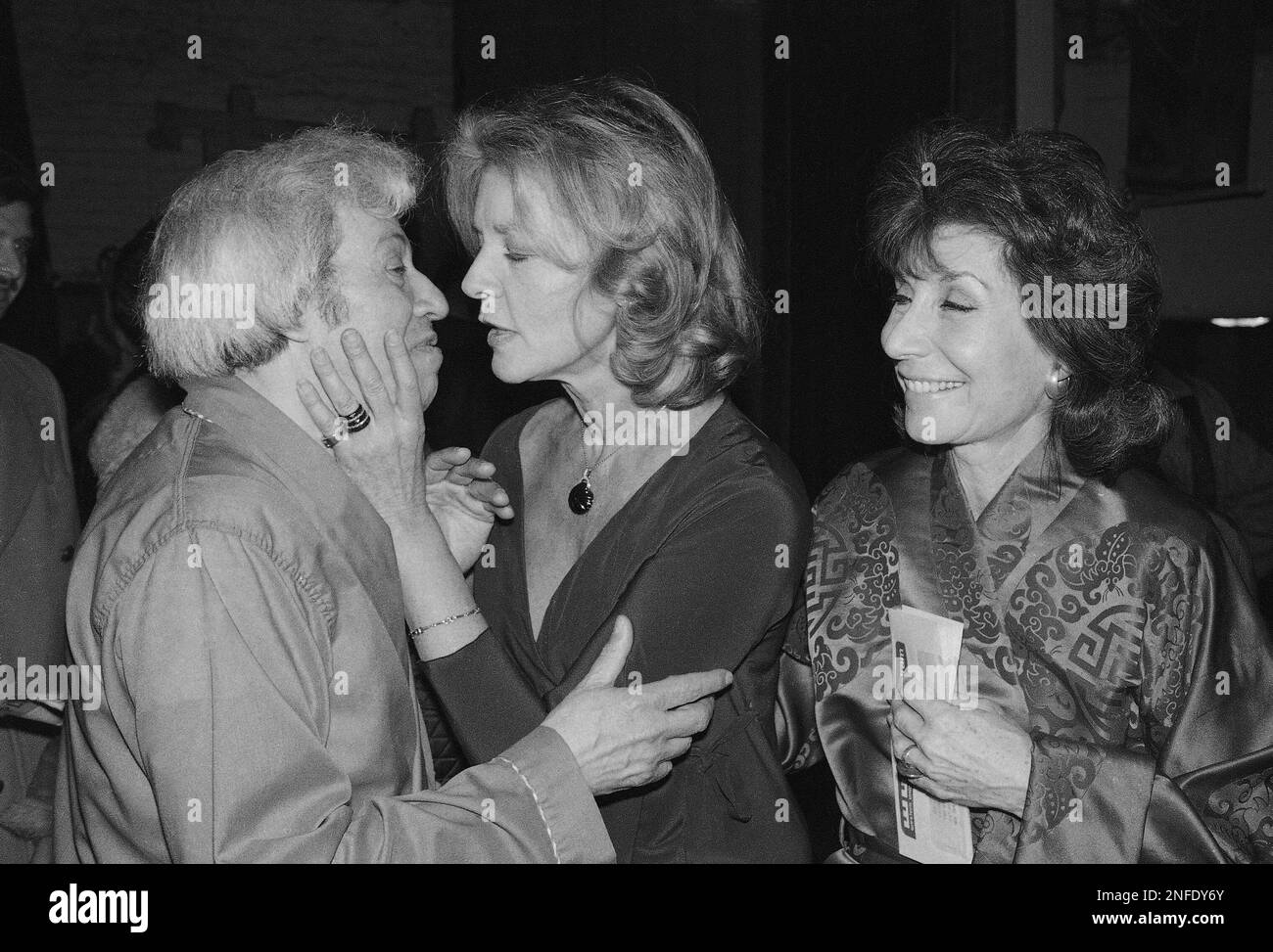 Actress Lauren Bacall prepares to kiss songwriter Adolph Green as Betty ...