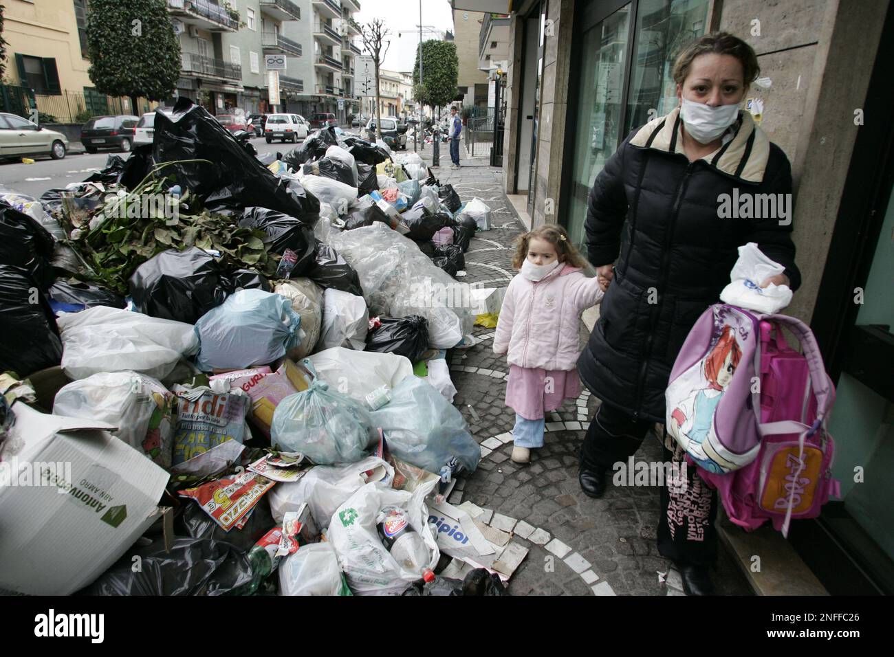A woman and a child walk past a pile of garbage, in Naples, Italy ...