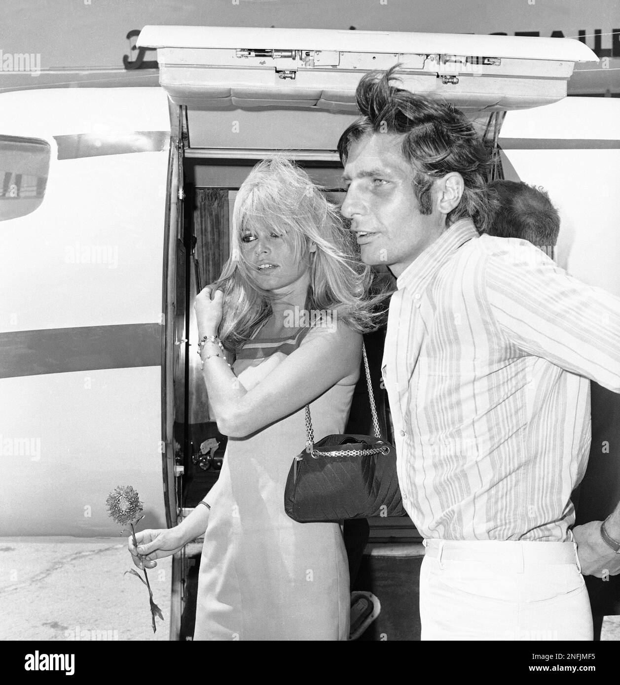 French film actress Brigitte Bardot clutches a single flower as she and her husband, German ...