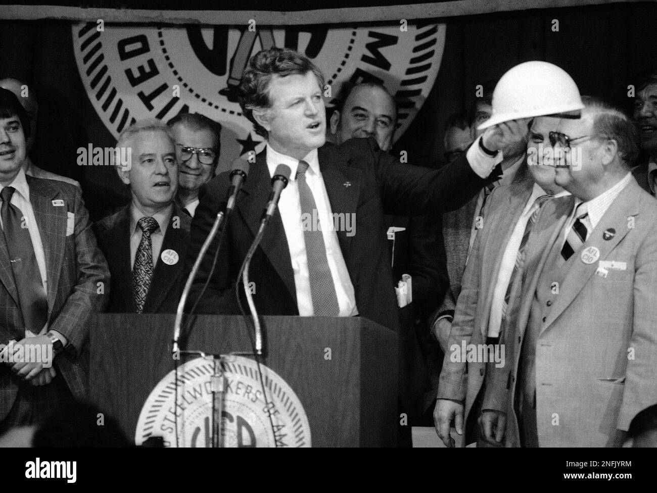 Sen. Edward Kennedy, center, holds up a steelworkers hard hat that was ...