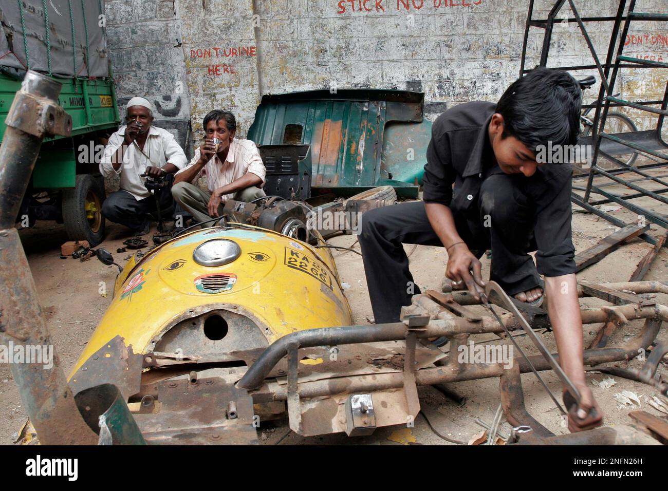 Elders drink tea, as a child laborer works at a garage, on World Day ...