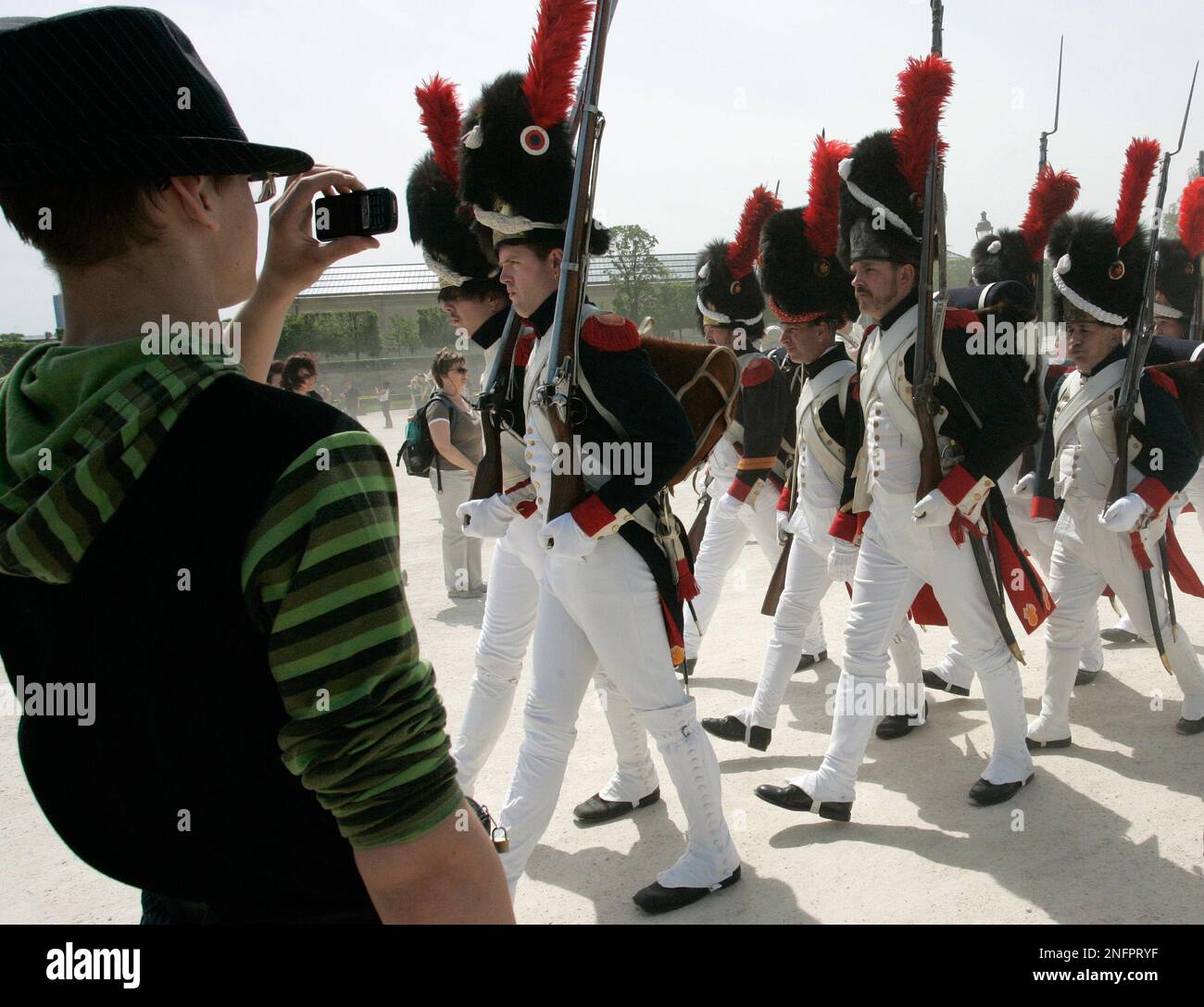 A tourist takes a snapshot of Napoleonic history enthusiasts dressed as ...