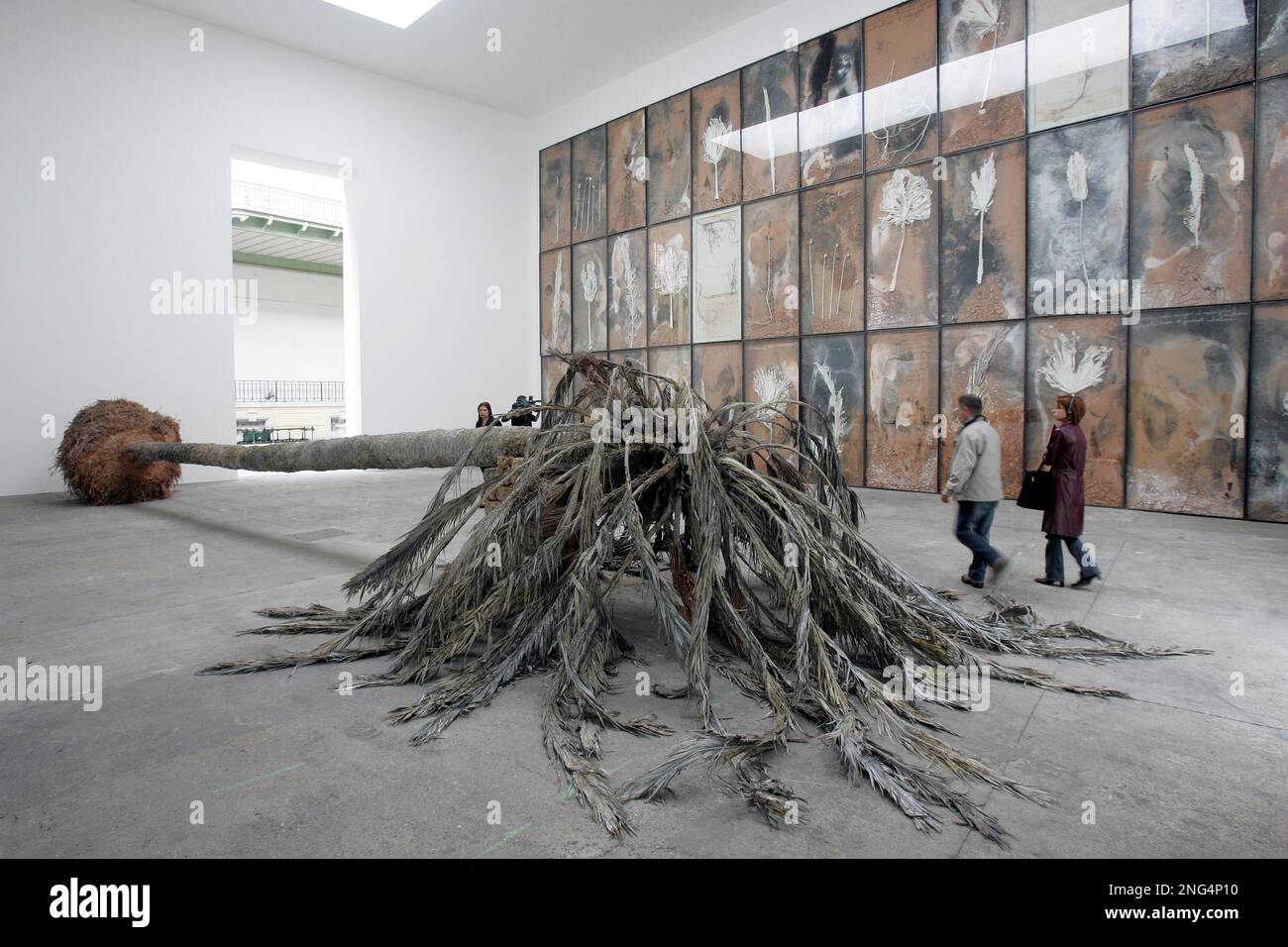 Visitors walk past a dead palm tree, part of "Palm Sunday" by German ...