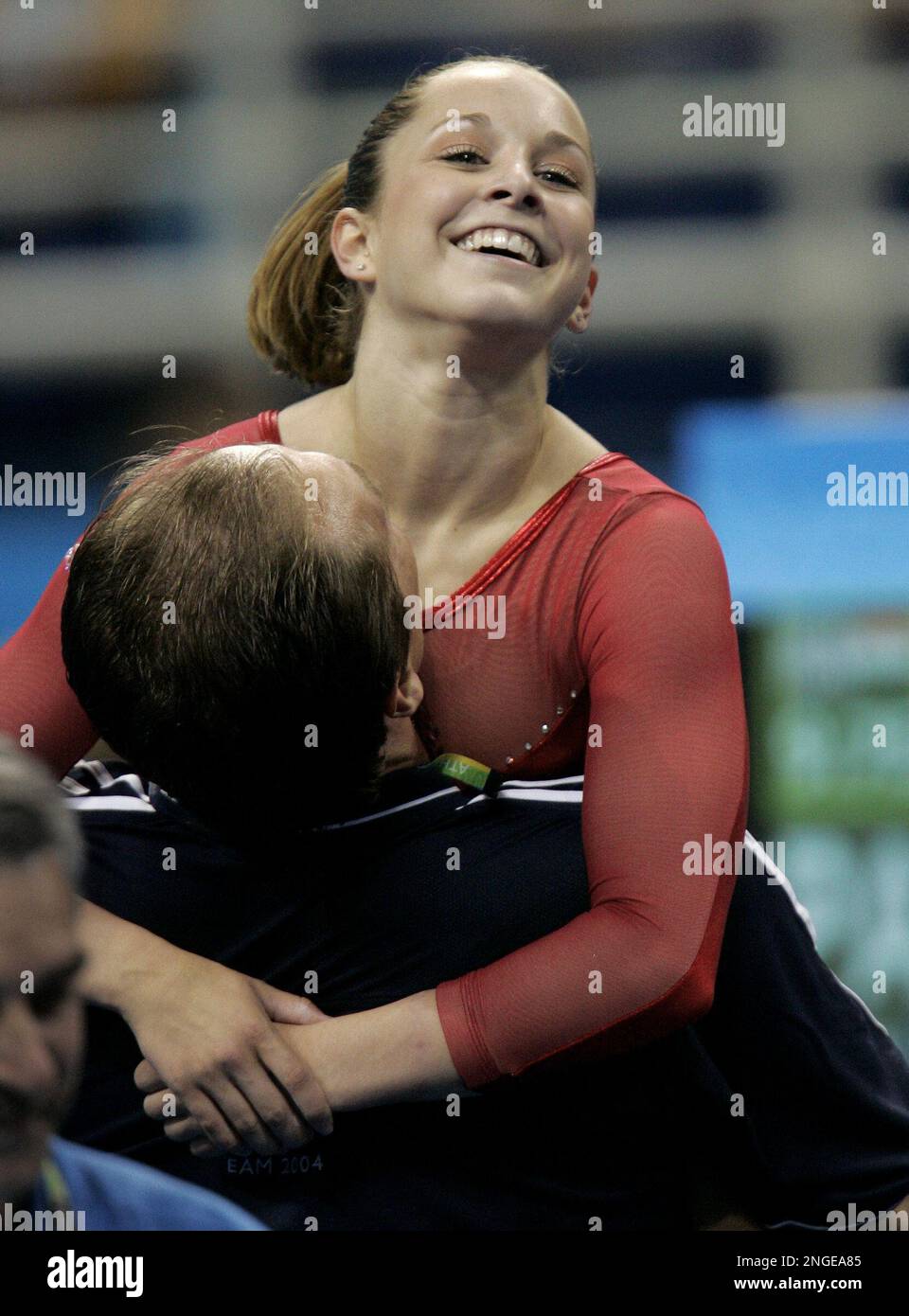 Carly Patterson, of the United States, is hoisted by her coach Evgeny ...