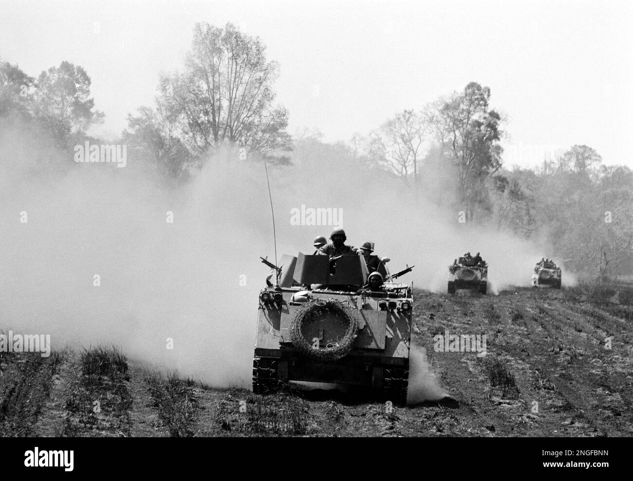 Armored vehicles kick up clouds of dust as they roll northward across a ...