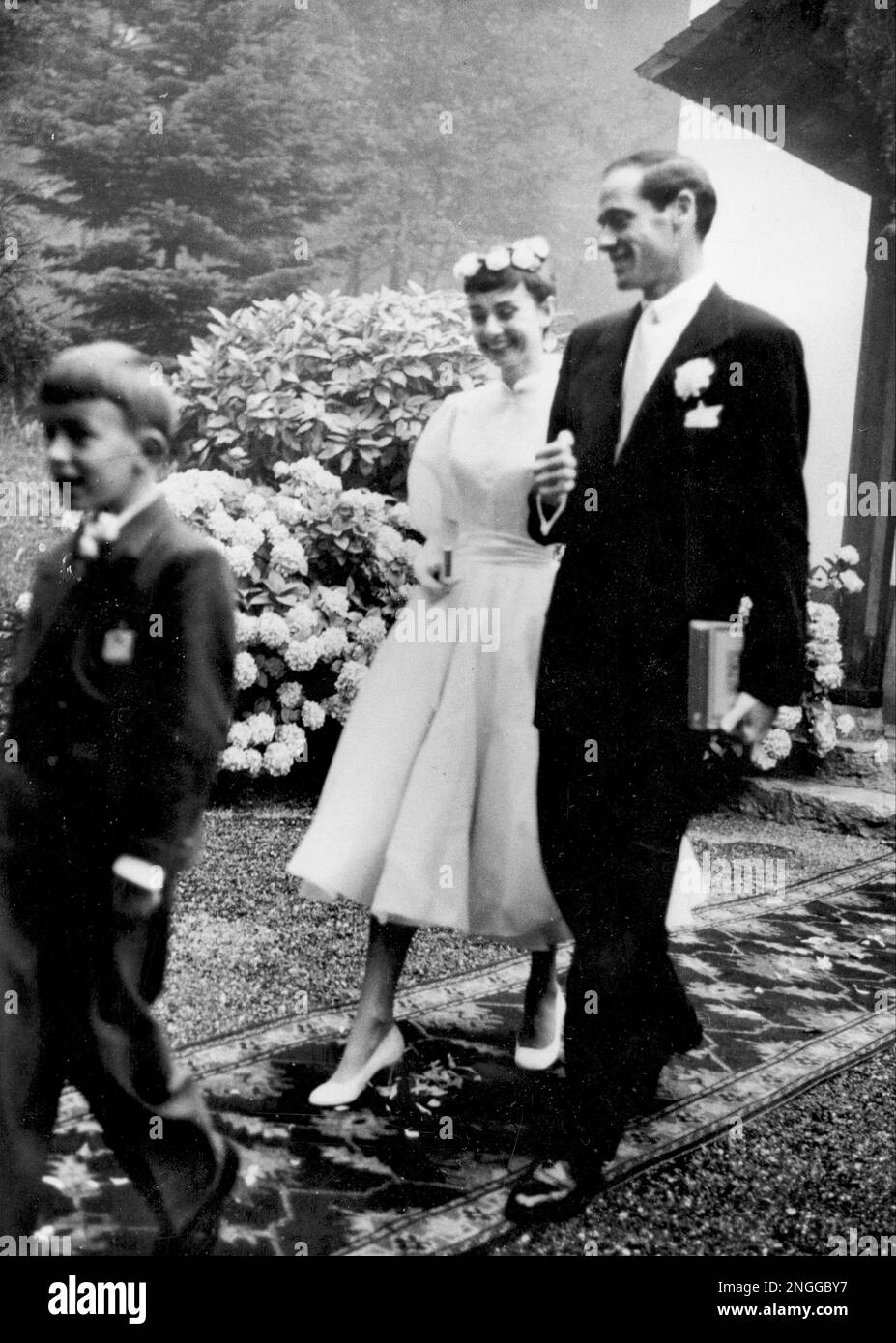 Actress Audrey Hepburn,22, and actor Mel Ferrer, 37, follow a page boy ...